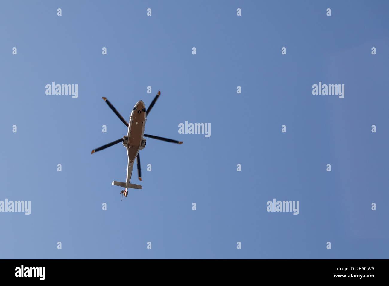 Helicopter flying in the blue sky bottom view Stock Photo - Alamy