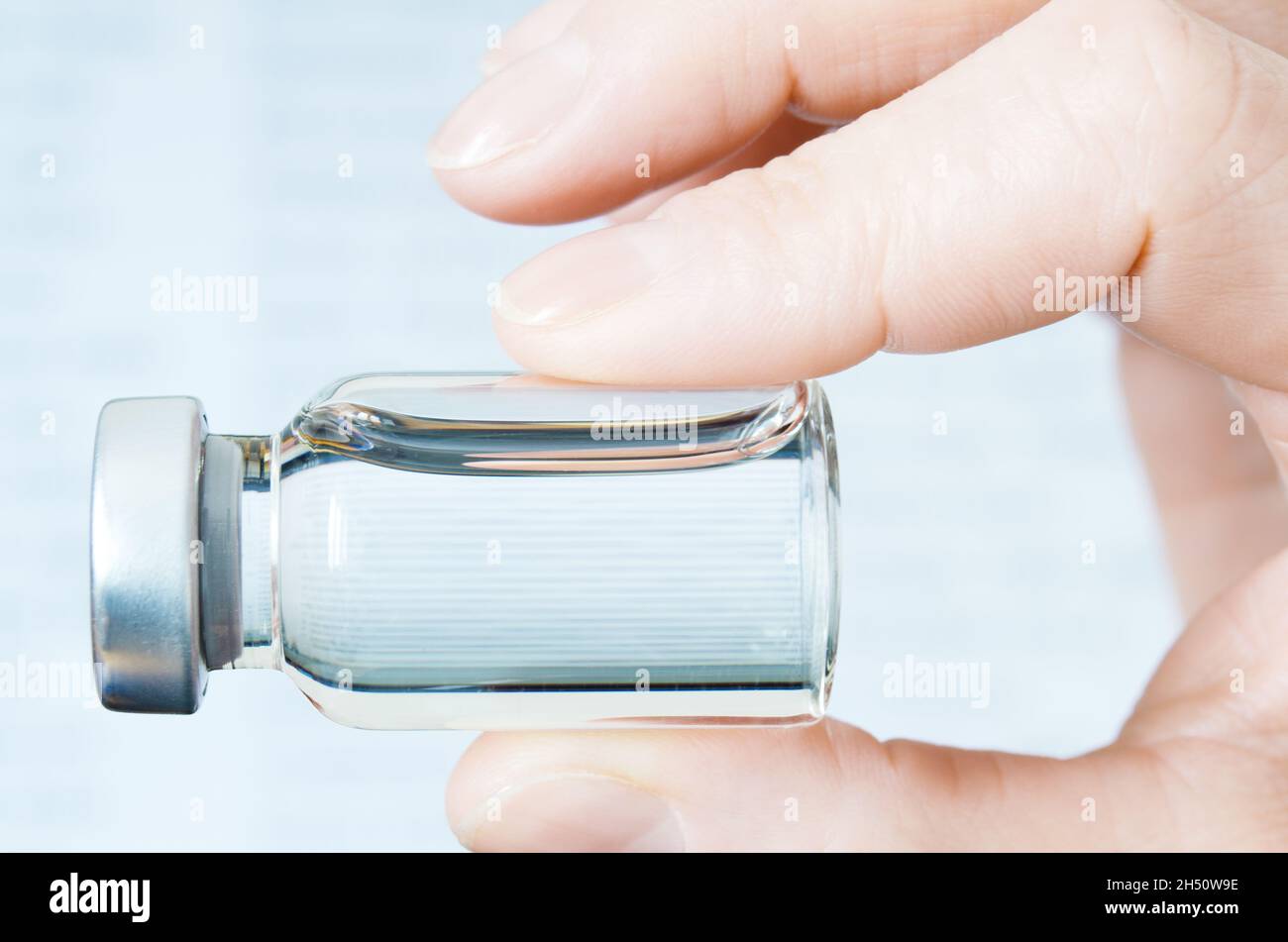 Glass vial with liquid medication in caucasian female fingers ...