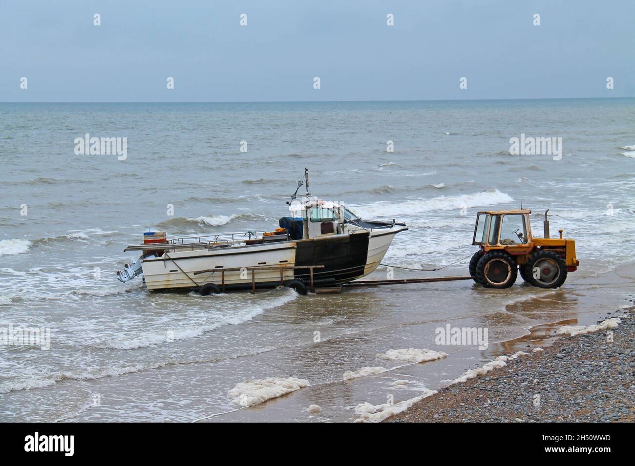 A Small Fishing Boat Being Towed from the Sea by Tractor Stock Photo ...