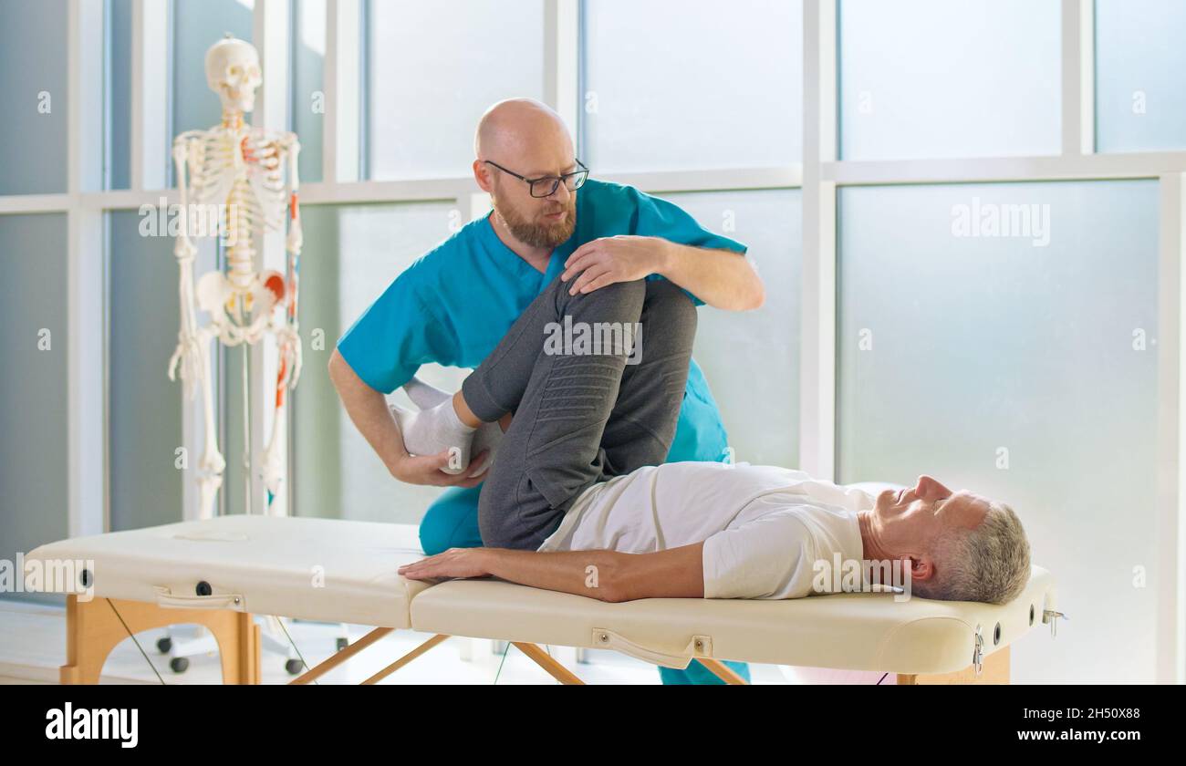 An Adult Man Trains Muscle Strength With a Professional Doctor in a ...