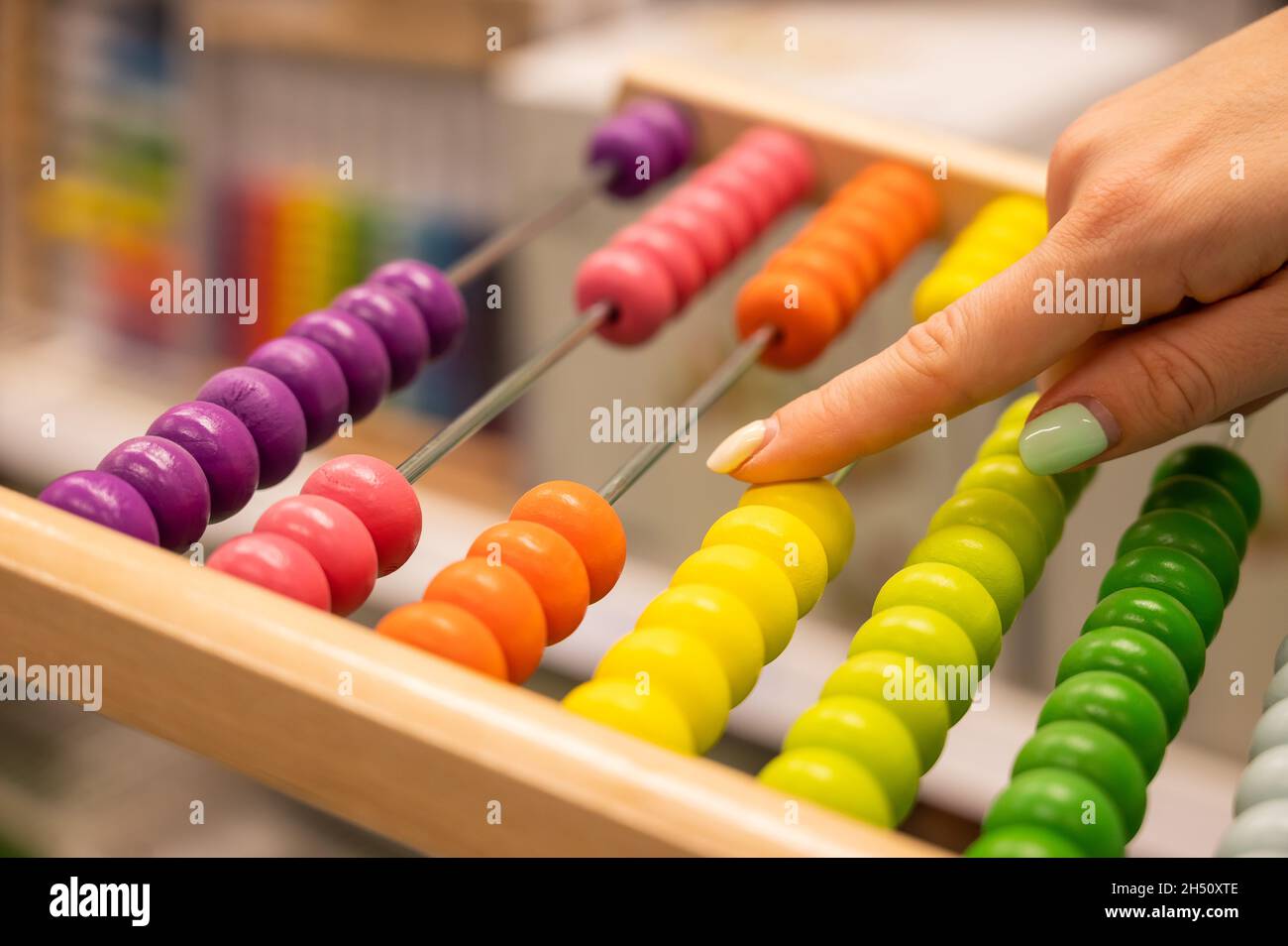 Closeup female hand calculating with balls on wooden rainbow abacus for ...