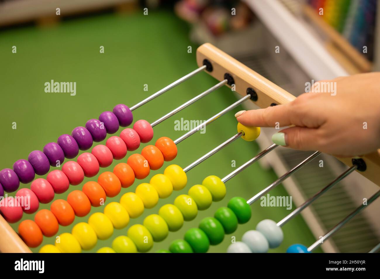 Closeup female hand calculating with balls on wooden rainbow abacus for ...