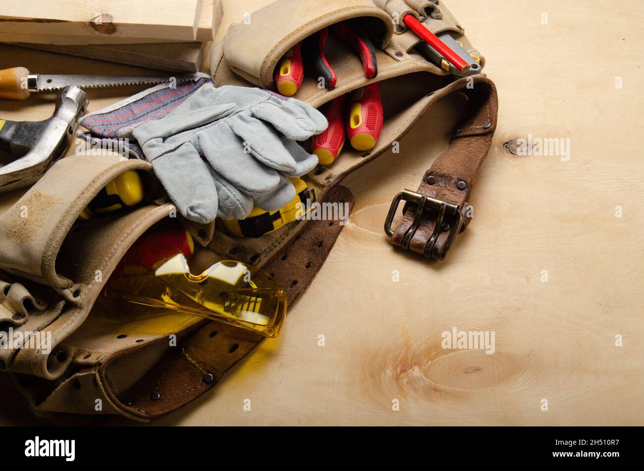 Tool belt with carpenter tools and protective wear on plywood sheet ...