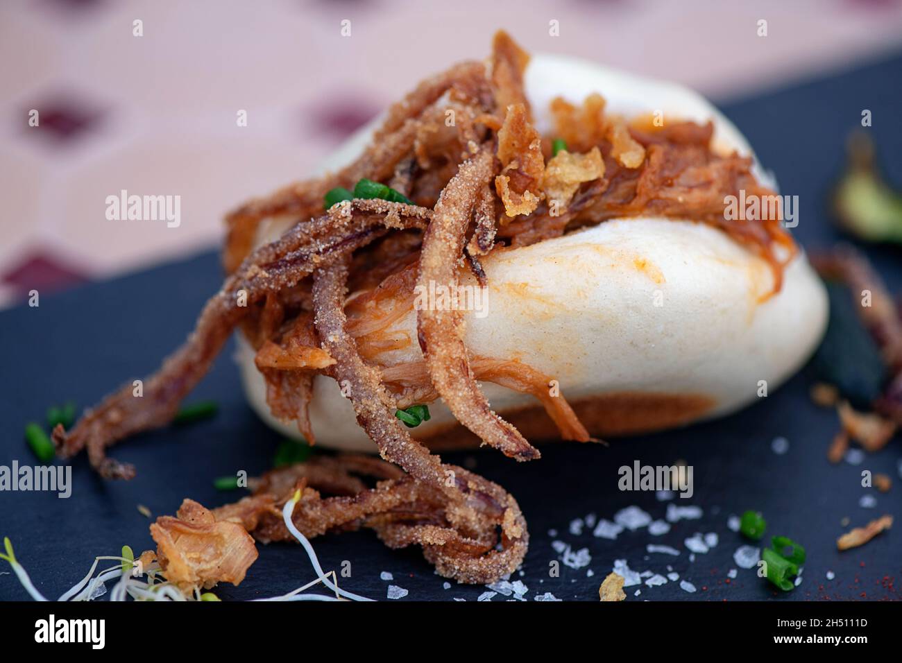 Steamed bao bun filled with pulled pork and caramelized onion and ...