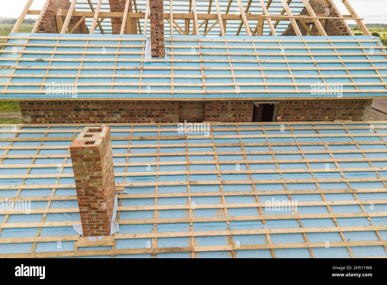 Aerial view of a brick house with wooden roof frame under construction ...