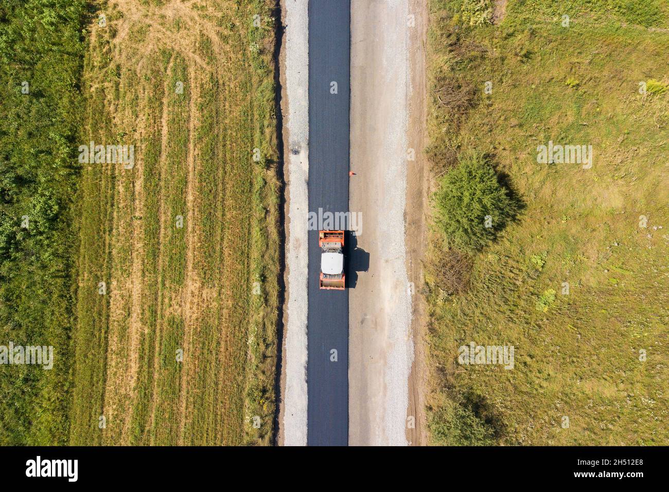 Aerial view of new road construction with steam roller machine at work ...