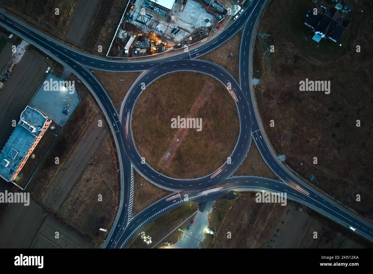 Aerial view of road roundabout intersection with fast moving heavy traffic at night. Top view of ...