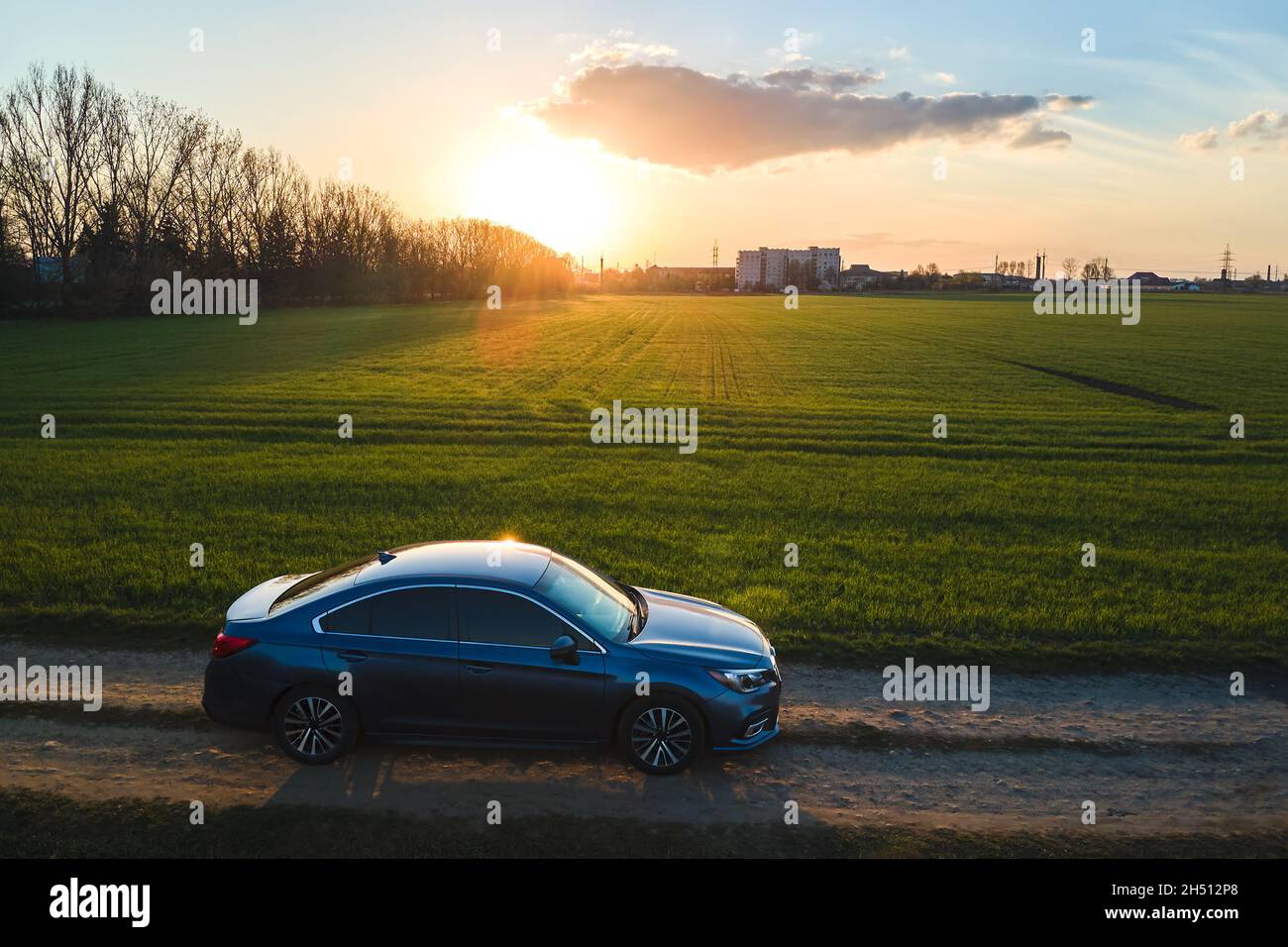 Aerial view of sedan car driving fast on dirt road at sunset. Traveling ...