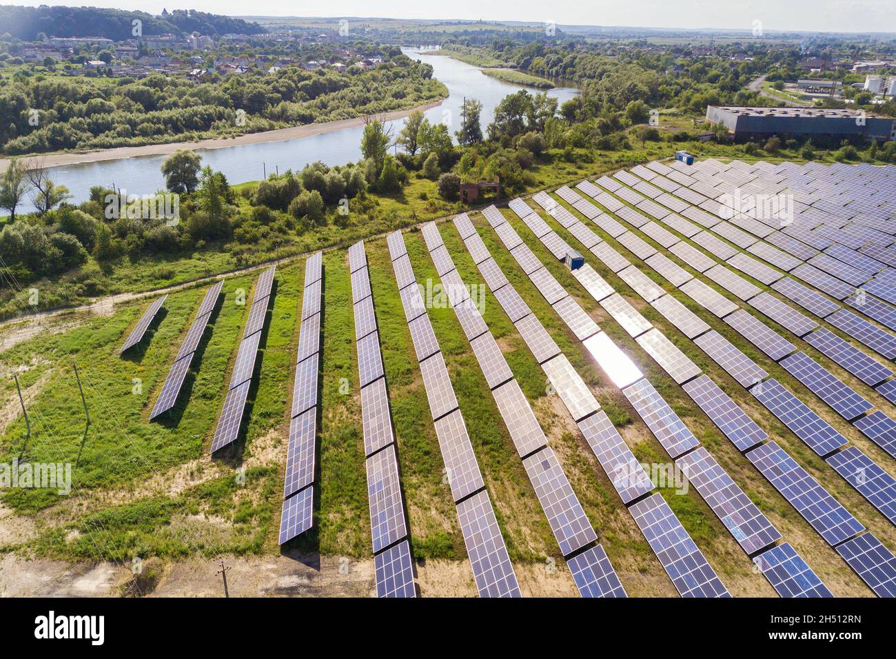 Aerial view of solar power plant on green field. Electric farm with panels for producing clean ...