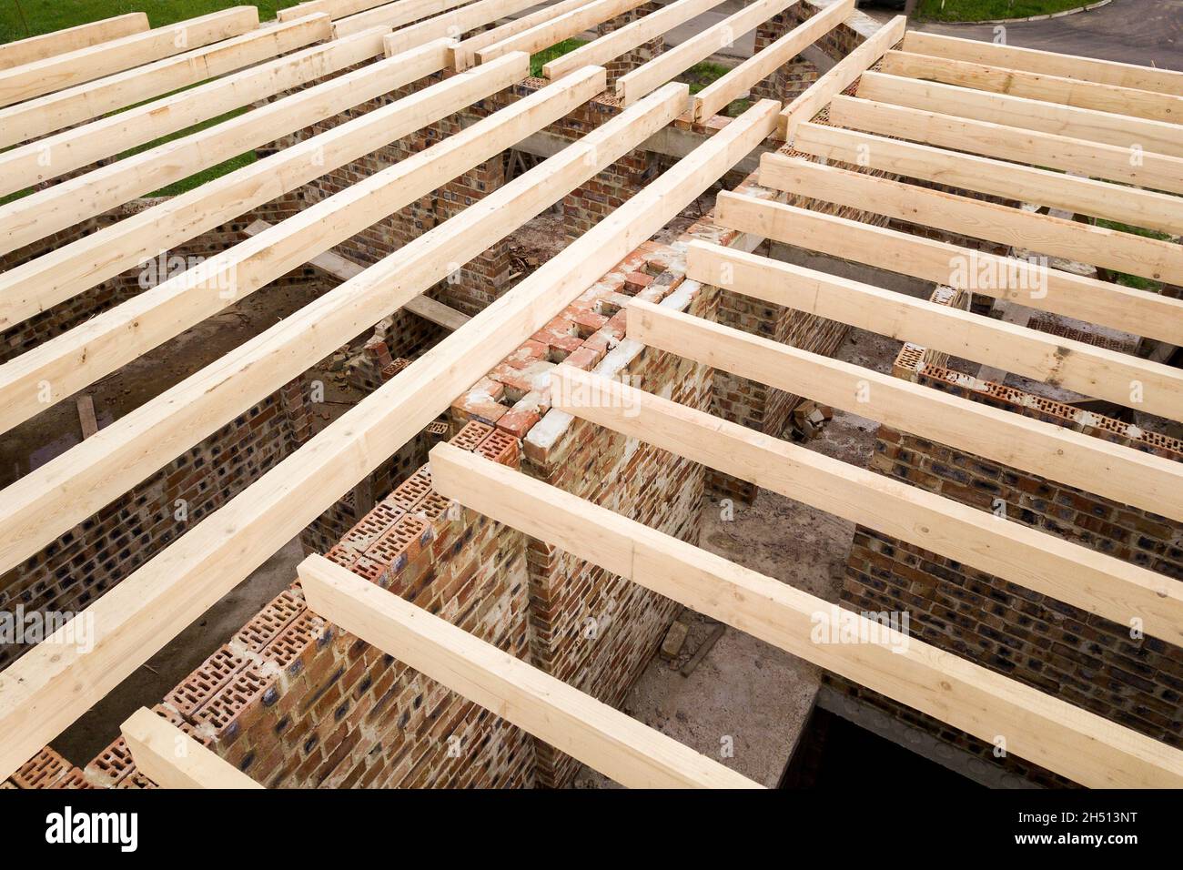 Close up of a brick house with wooden ceiling frame under construction ...
