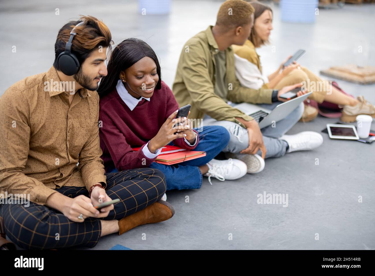 Students sit and use digital devices on asphalt Stock Photo - Alamy