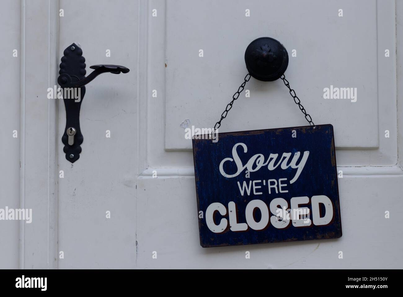 Sorry we are closed sign hanging on a white doors with door handle ...