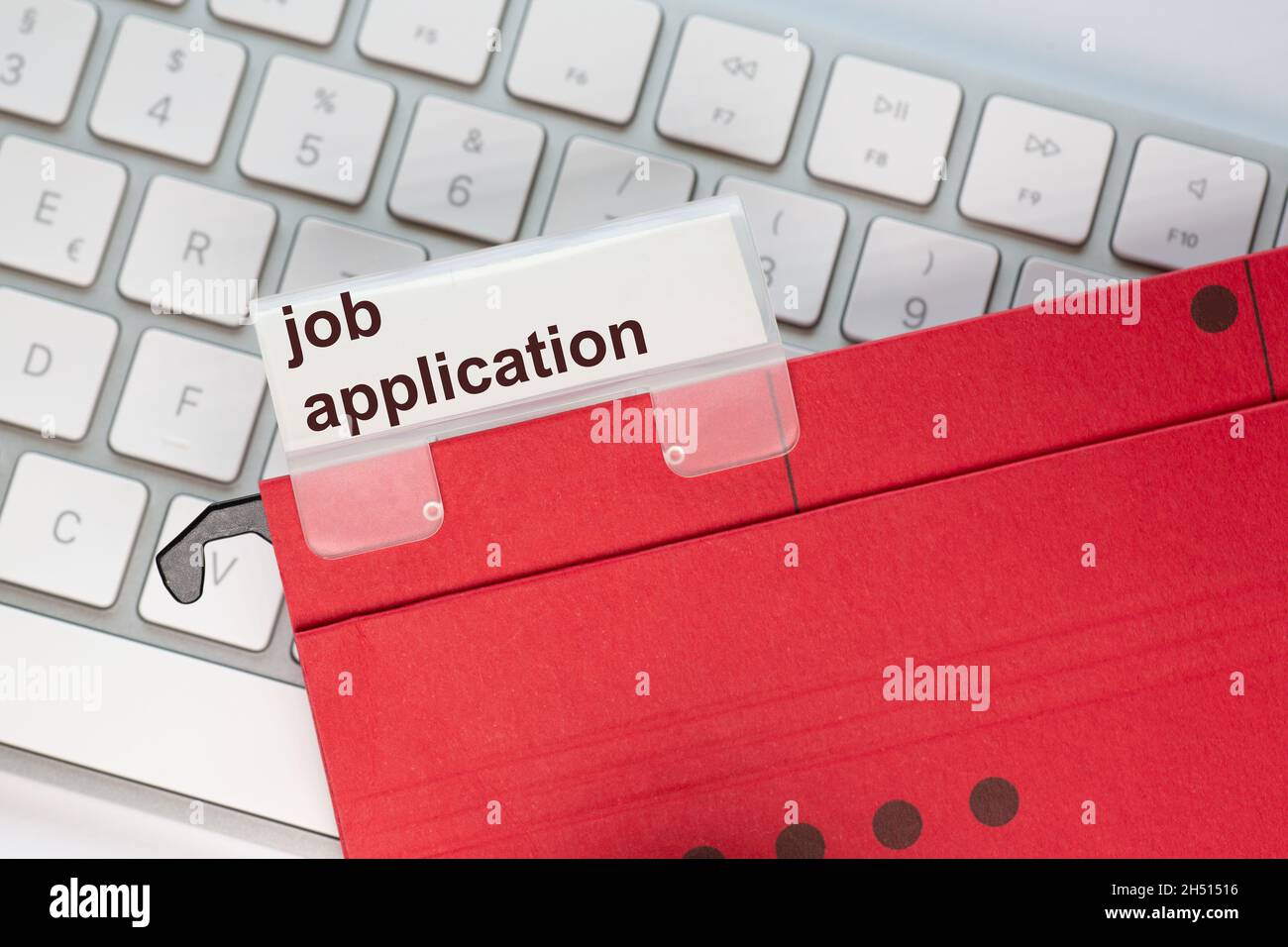 red hanging folder on a keyboard has a tab with the words Job ...