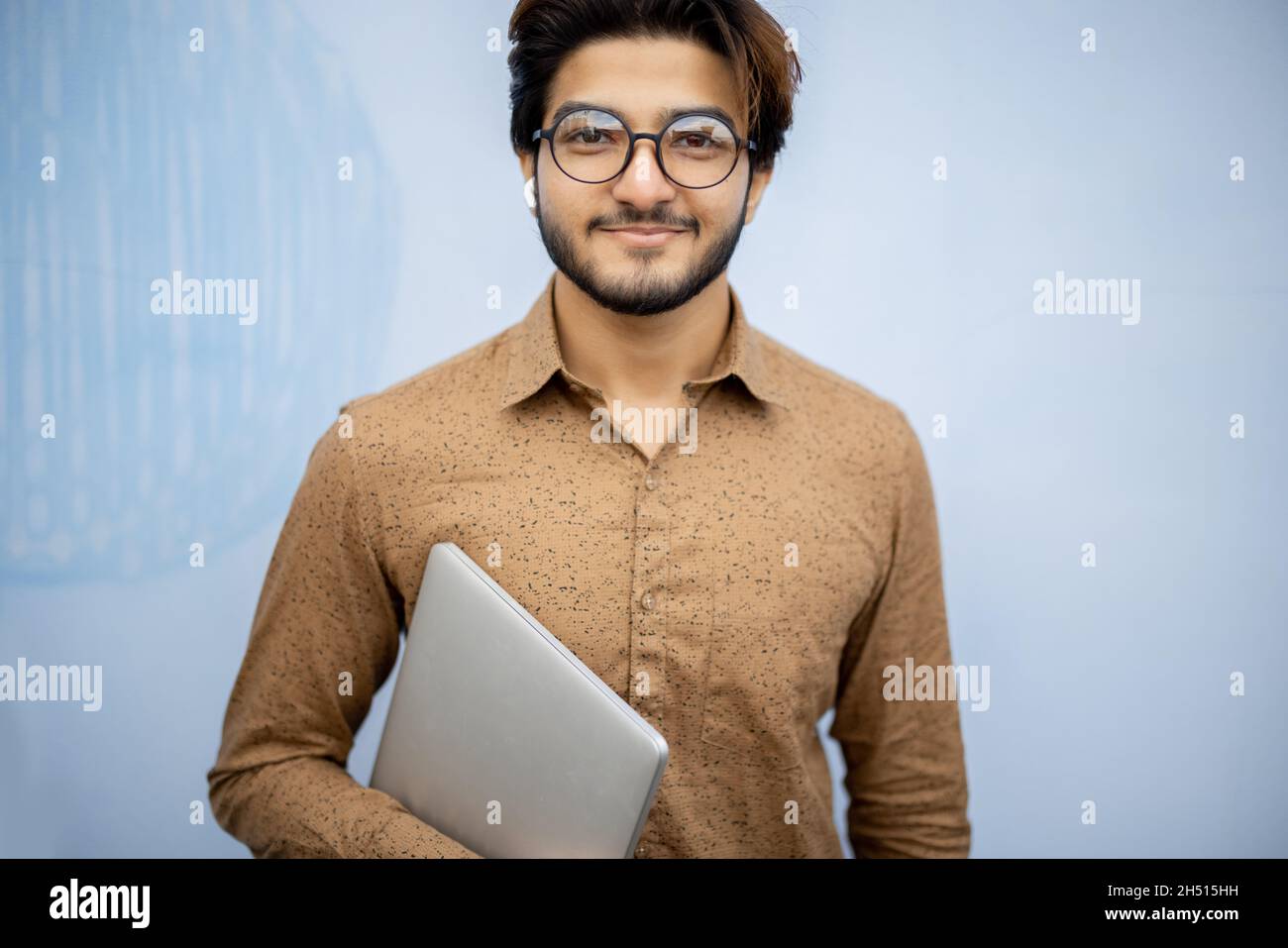 Young indian man with laptop looking at camera Stock Photo - Alamy