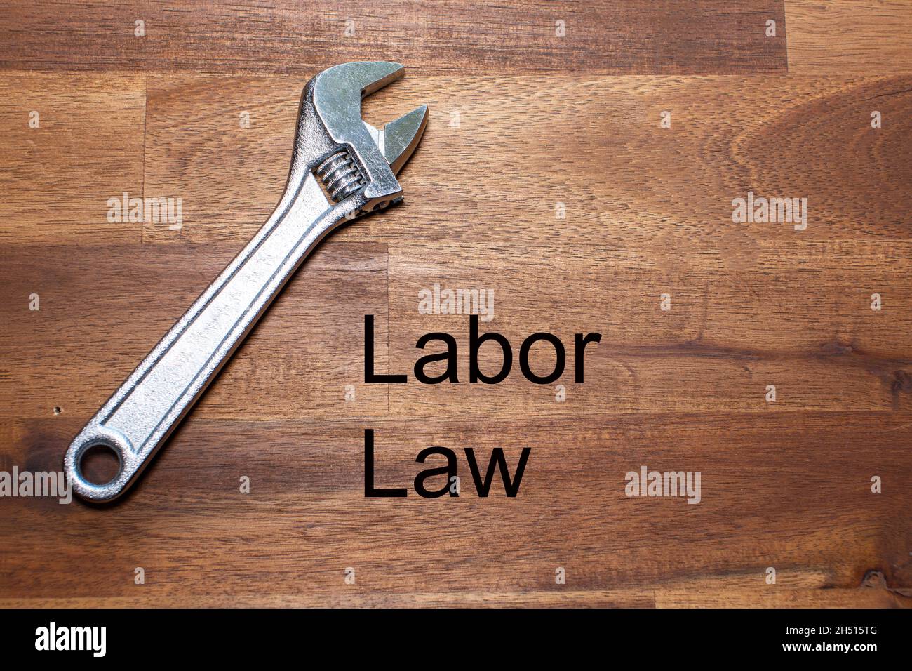 a flexible chromed adjustable wrench lies on a dark wooden table. The ...