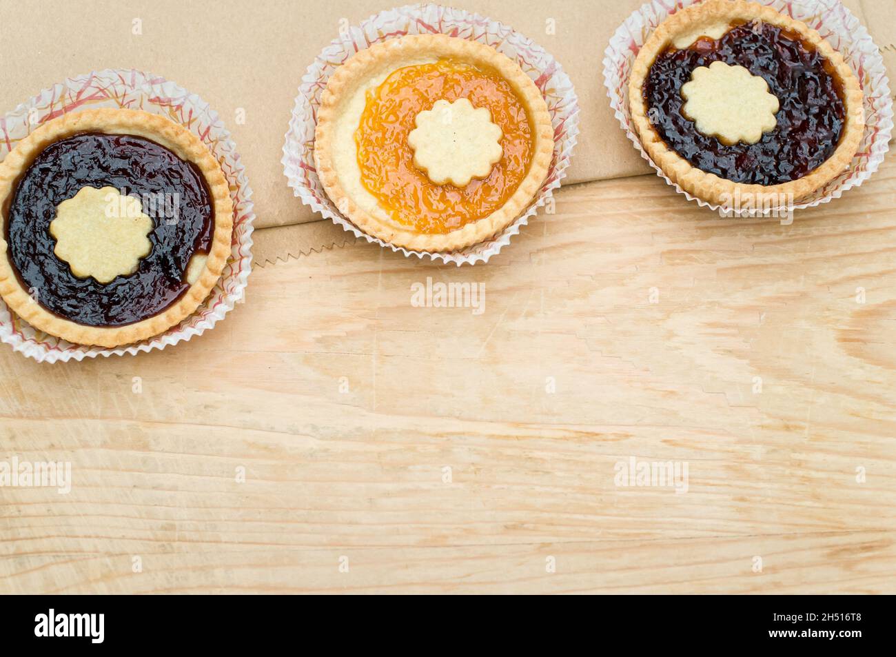 apricot and cherry jam short crust pastry on a food paper and wooden ...