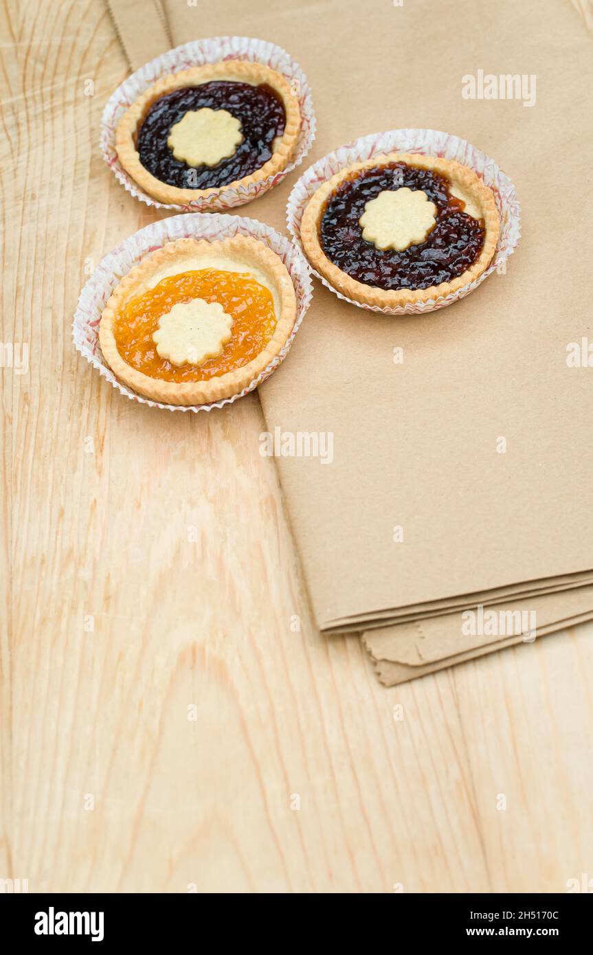 short crust pastry with jam on a food paper and rustic wooden tabletop ...