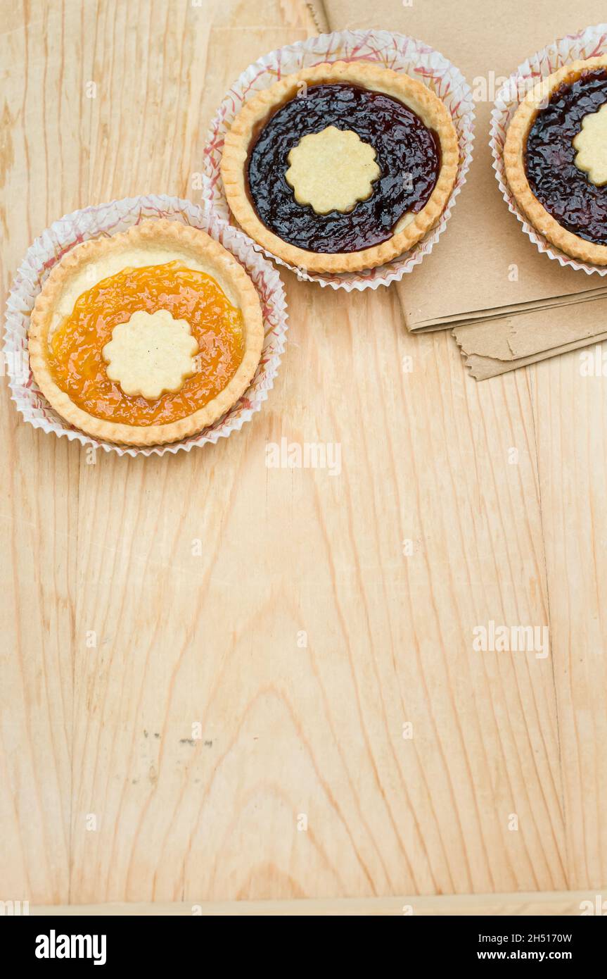 short crust pastry with jam on a food paper and rustic wooden tabletop ...