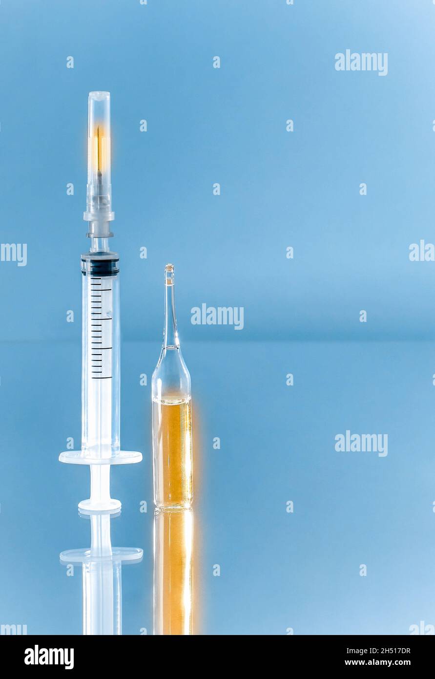 A syringe with a burning needle and divisions next to a glass ampoule ...