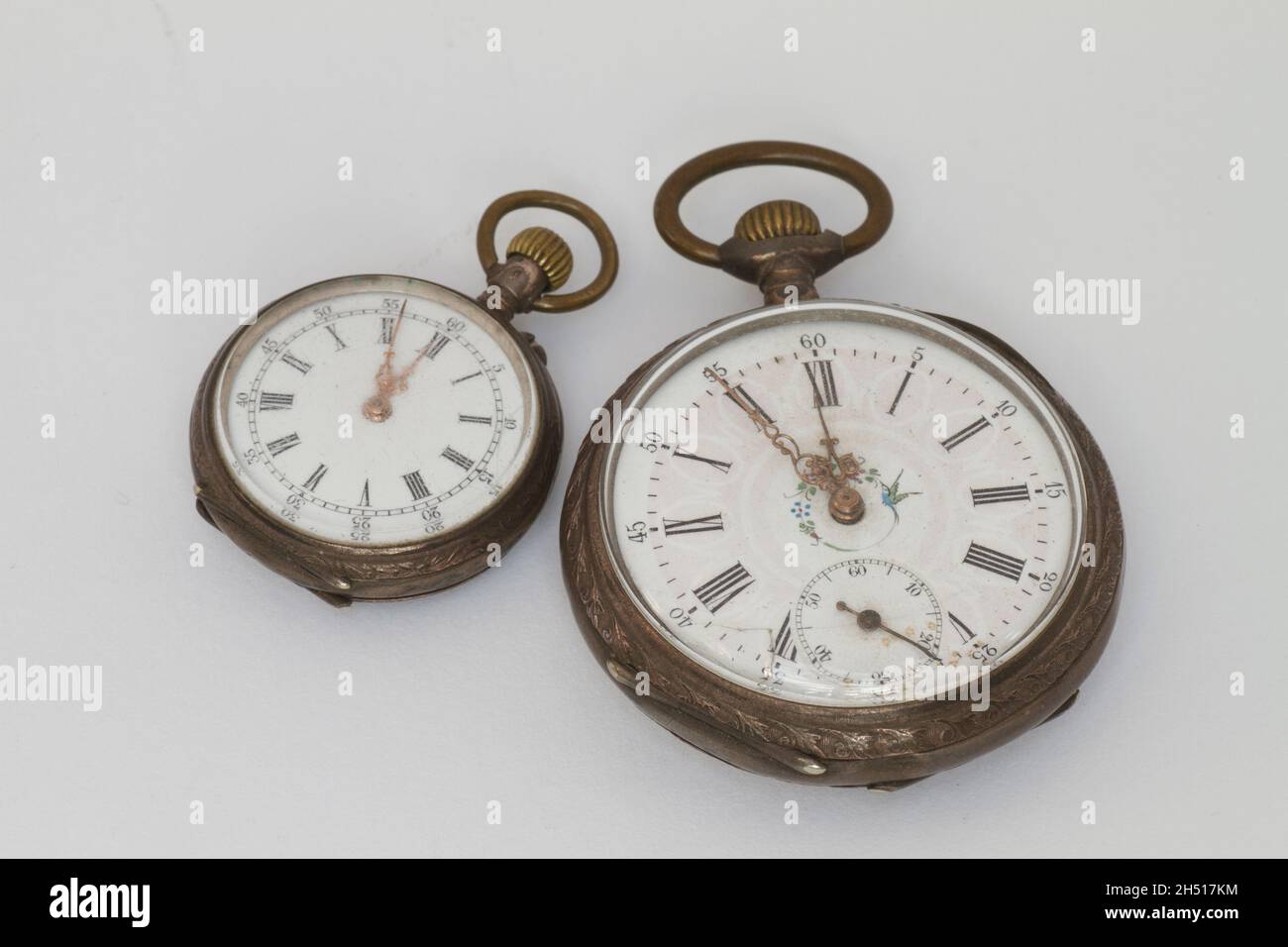 two antique pocket watches with Roman numerals on the dial are isolated ...