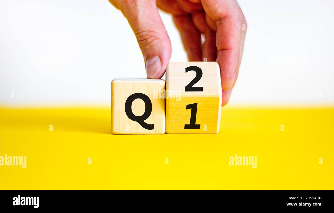 From 1st to 2nd quarter symbol. Businessman turns a wooden cube and ...