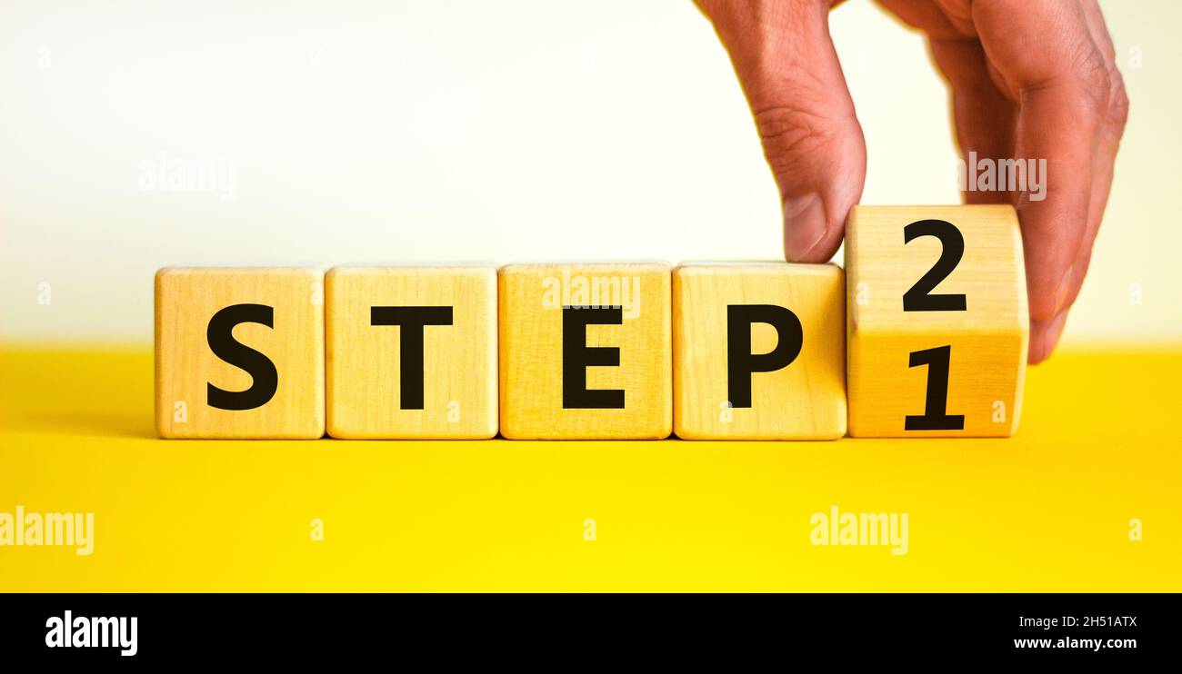 Step 1 or 2 symbol. Businessman turns a wooden cube and changes words ...