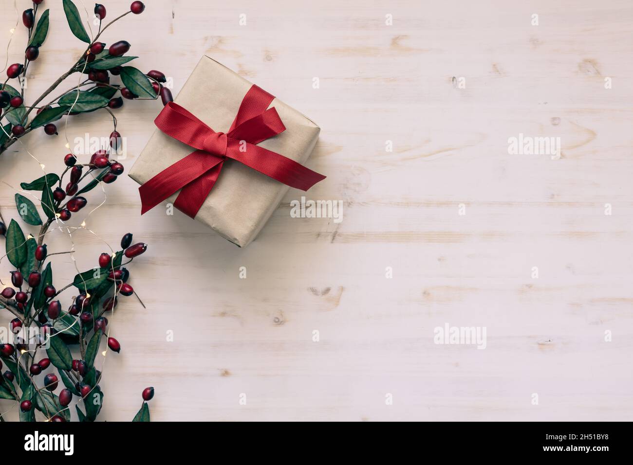 One Christmas parcel tied with a red ribbon bow on a white wood ...