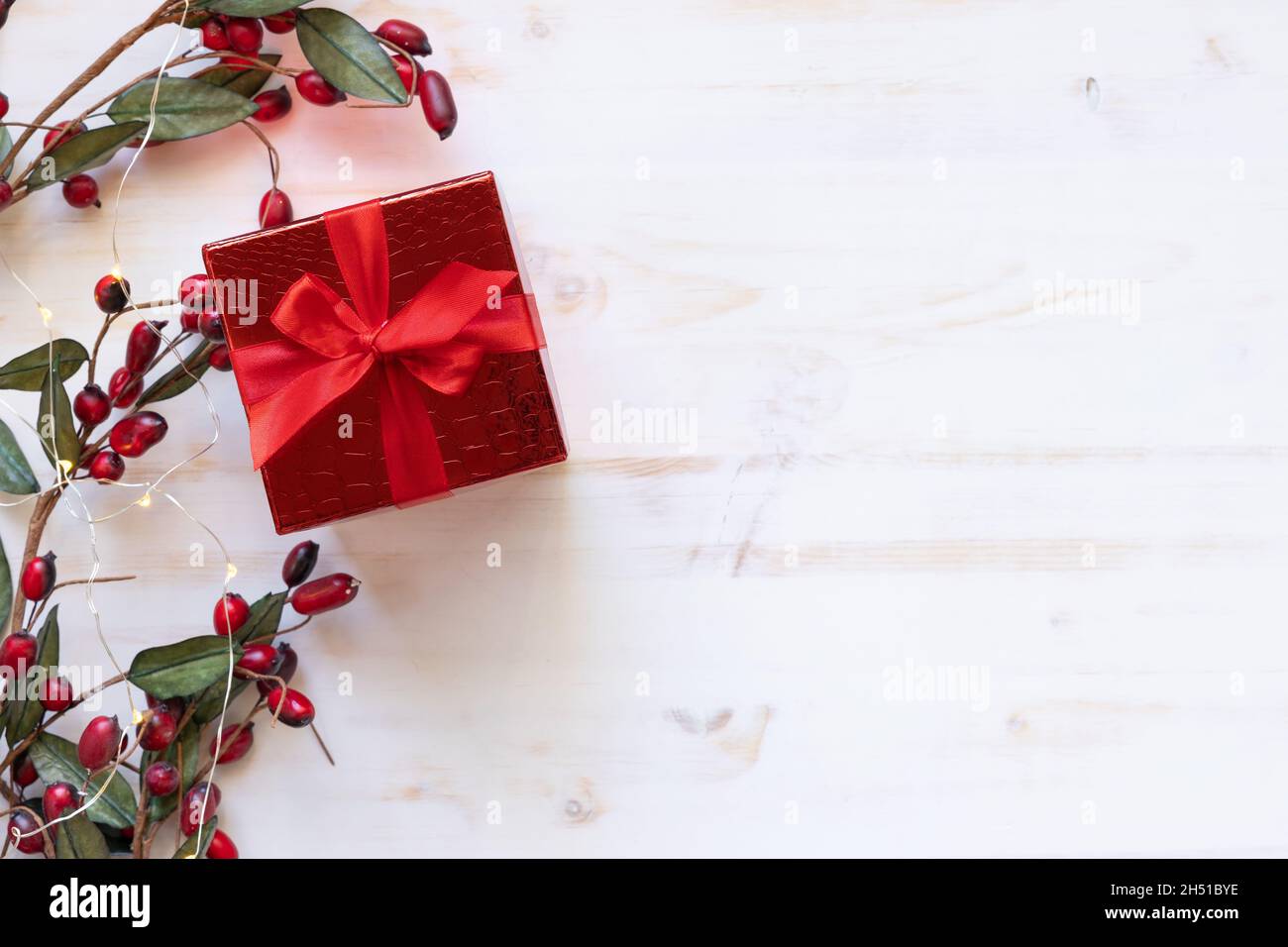 Single red shiny Christmas parcel on a white wood background with ...