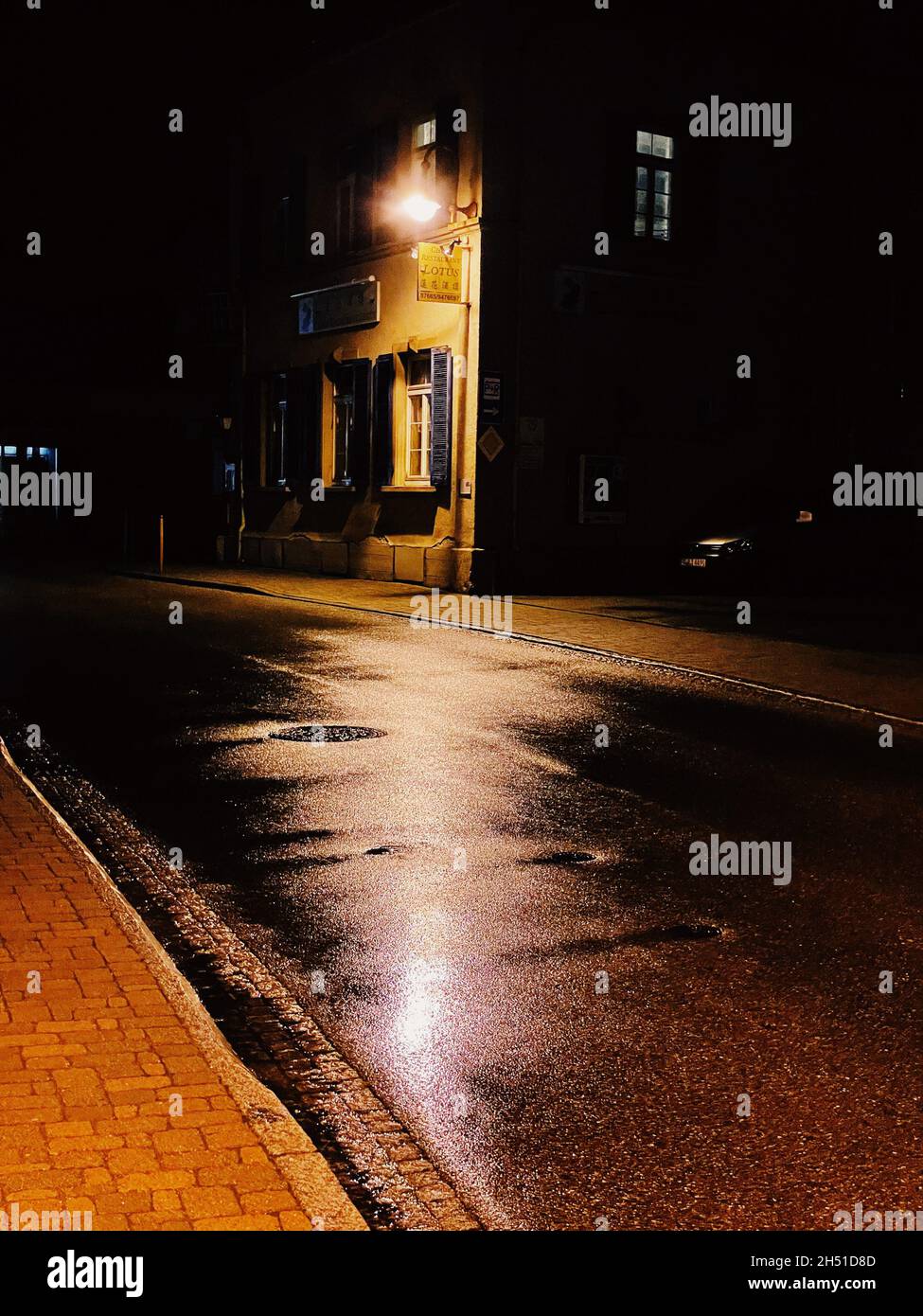 Downtown street and sidewalk at night with light from a lamppost ...