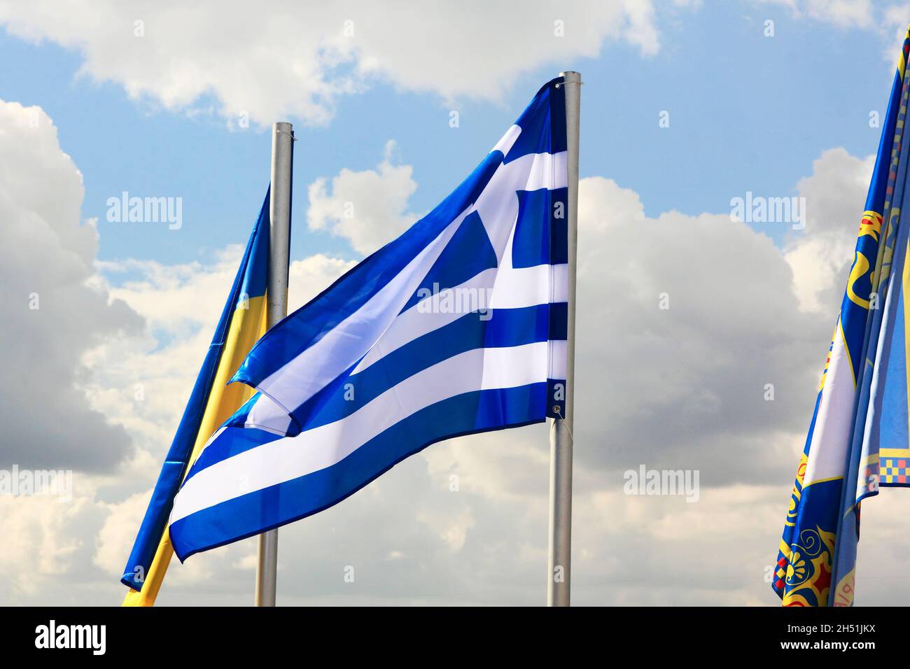 Greek flag, Ukranian flag and Mariupol city flag on a cloudy sky ...