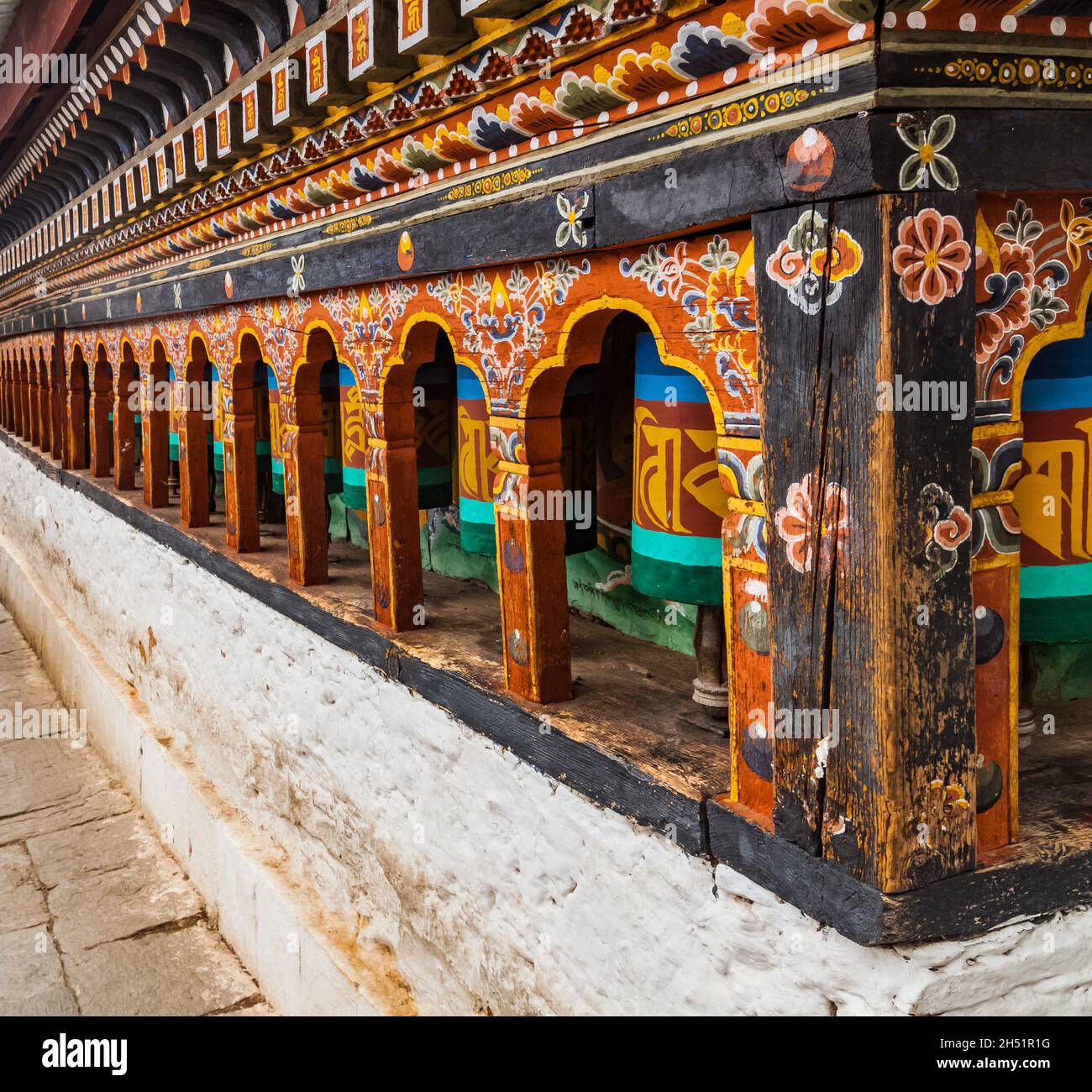 Row of painted turning prayer wheels mantra in Bhutan with traditional ...