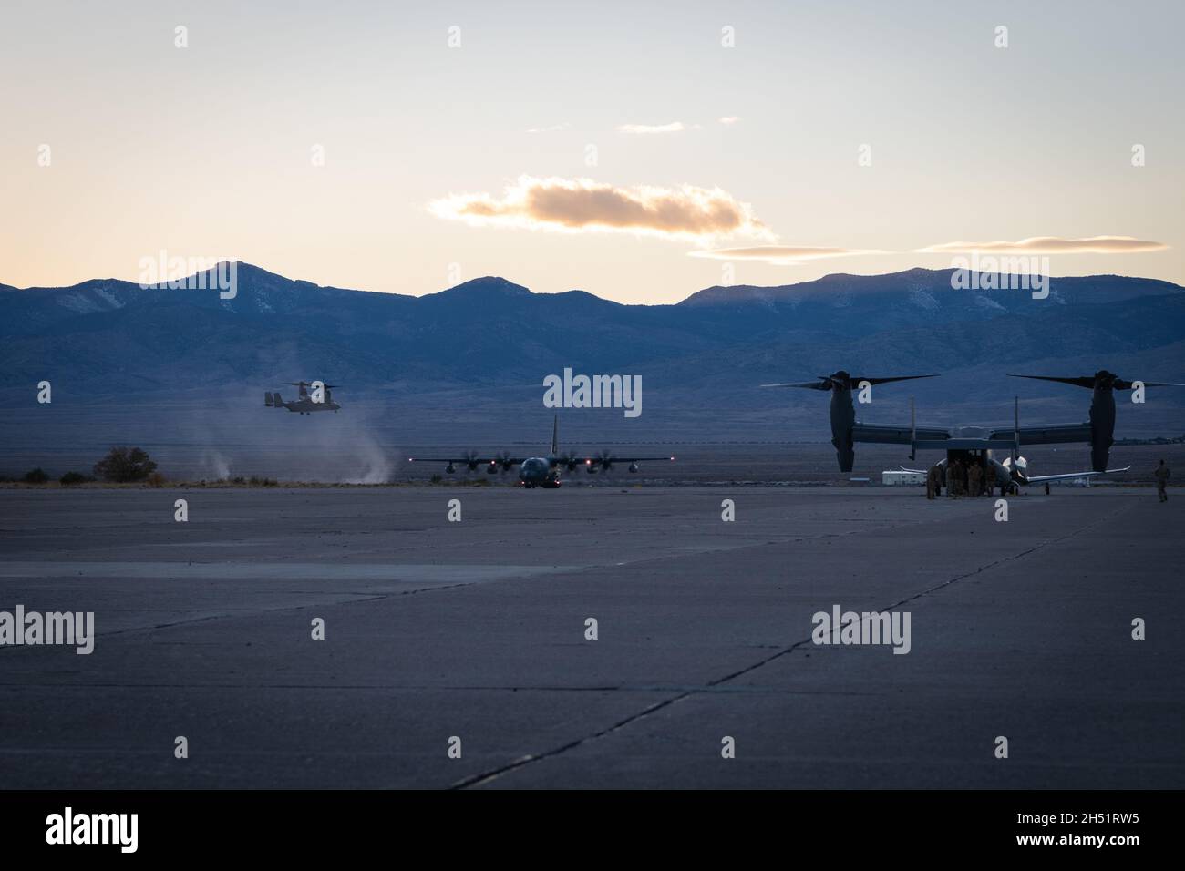 A CV-22 Osprey tiltrotor aircraft lands while an MC-130J Commando II ...