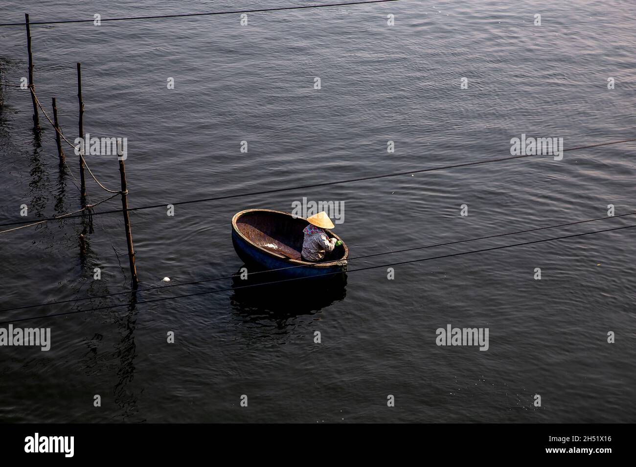 One person with conical hat floating in a round basket boat on the ...