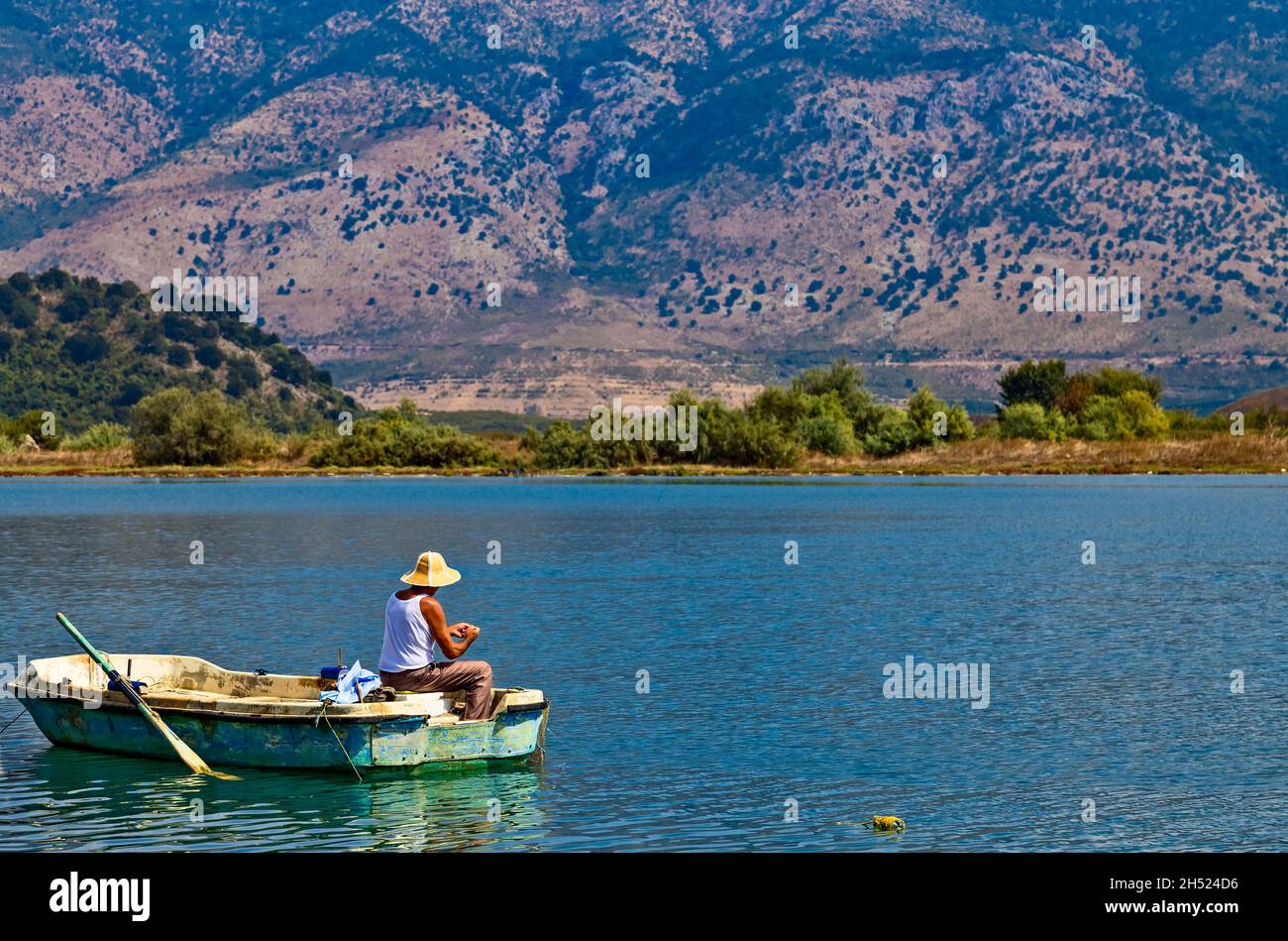 An albanian fisherman in his boat on Butrint lake salt lagoon, view ...