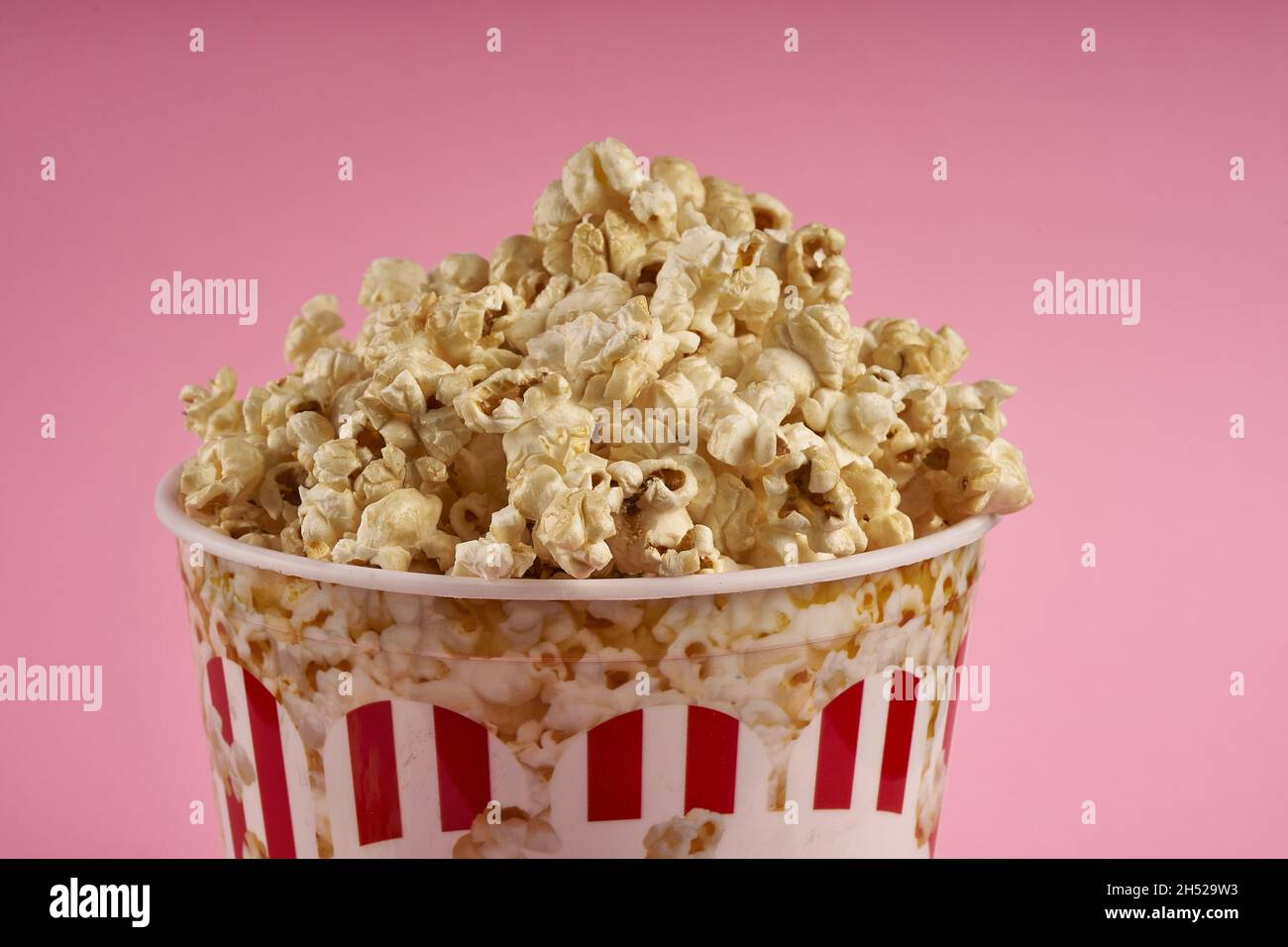Bucket full of sweet popcorn on pink background Stock Photo - Alamy