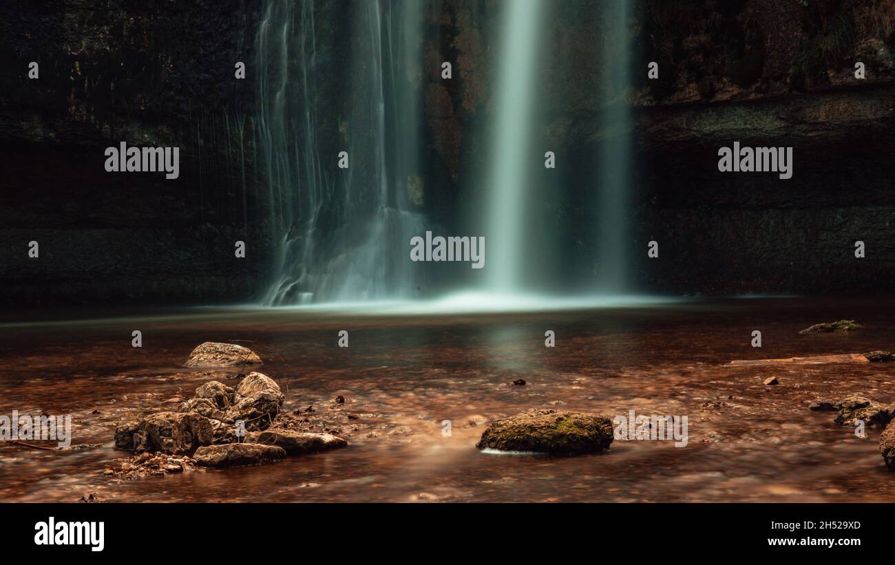 Beautiful scenery of a heavy flowing waterfall on a rocky ground inside ...