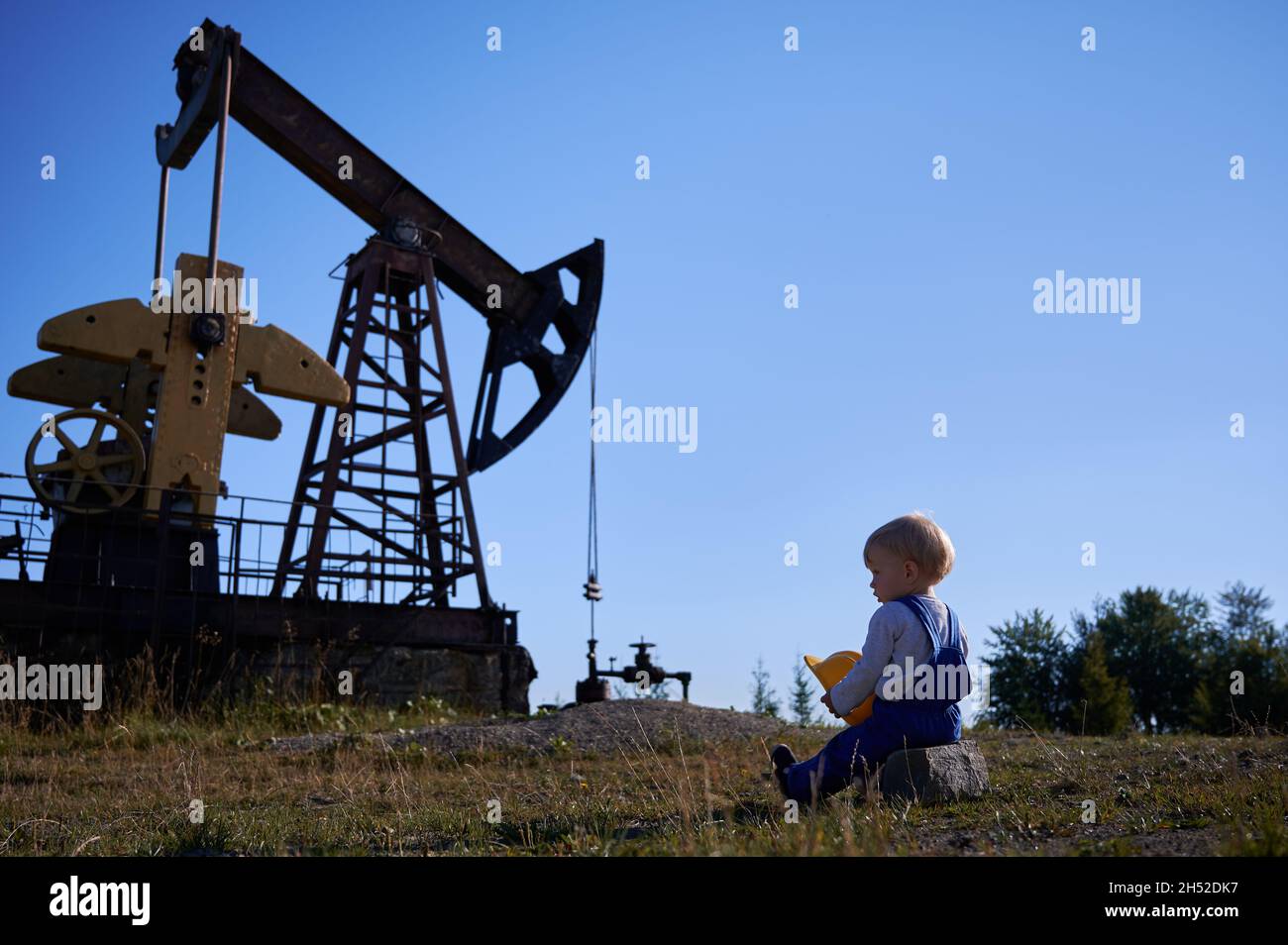 Rear view of preschool guy sitting on one stone, holding construction ...