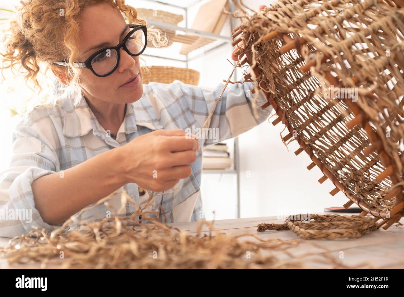 Close up of adult woman making wicker lamp at home alone in hobby diy ...