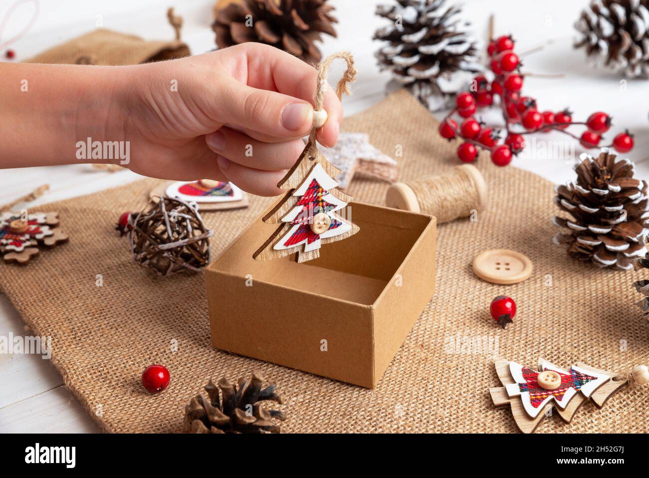 Kid hand drop a small decorative Christmas tree into the gift box. The ...
