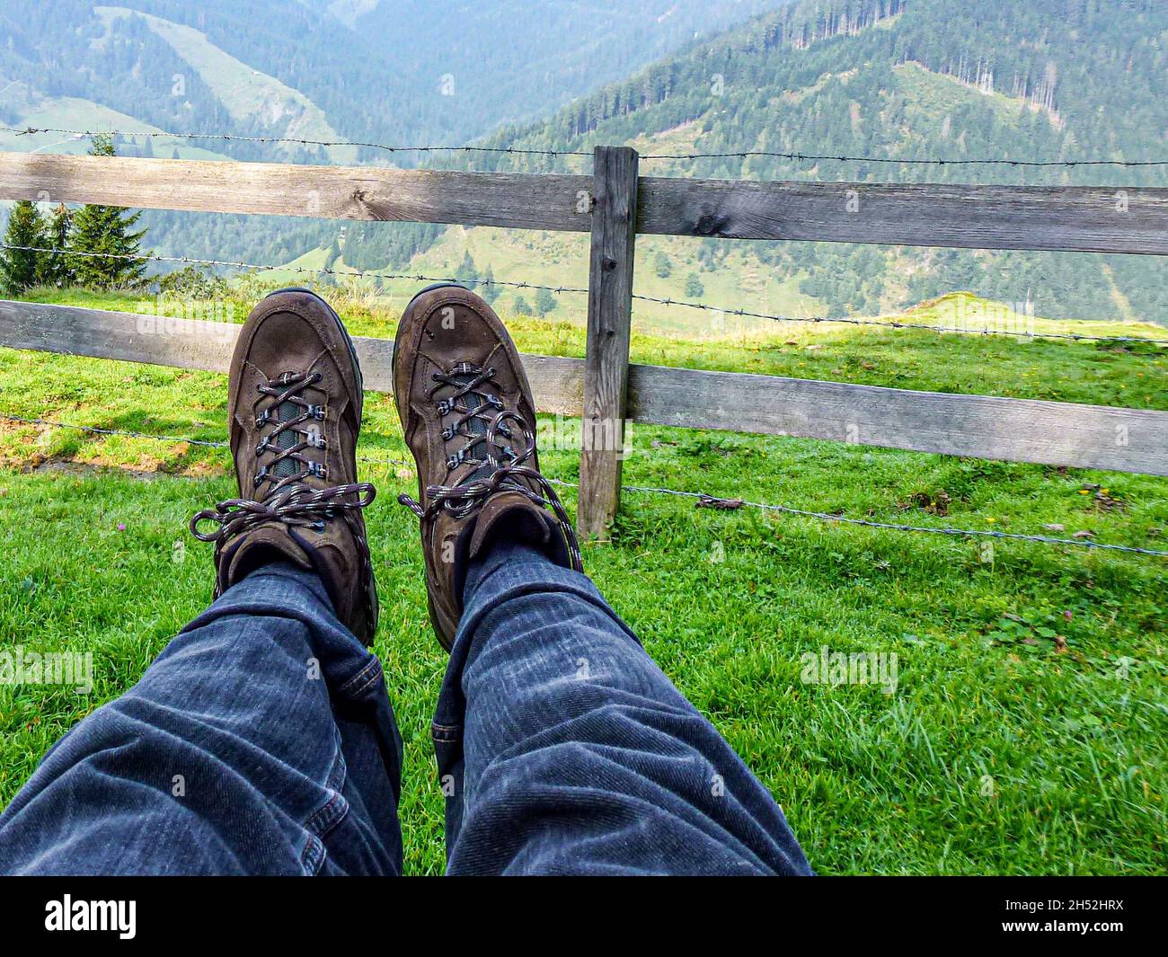 Male's feet lying on the grass in a fenced farm on the hills Stock ...