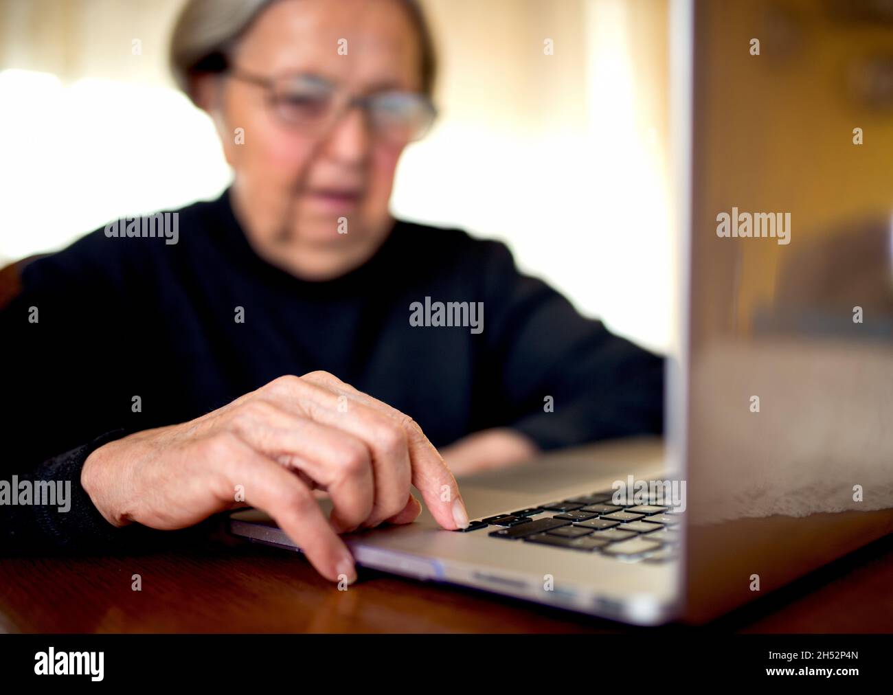 Old woman typing on laptop Stock Photo - Alamy