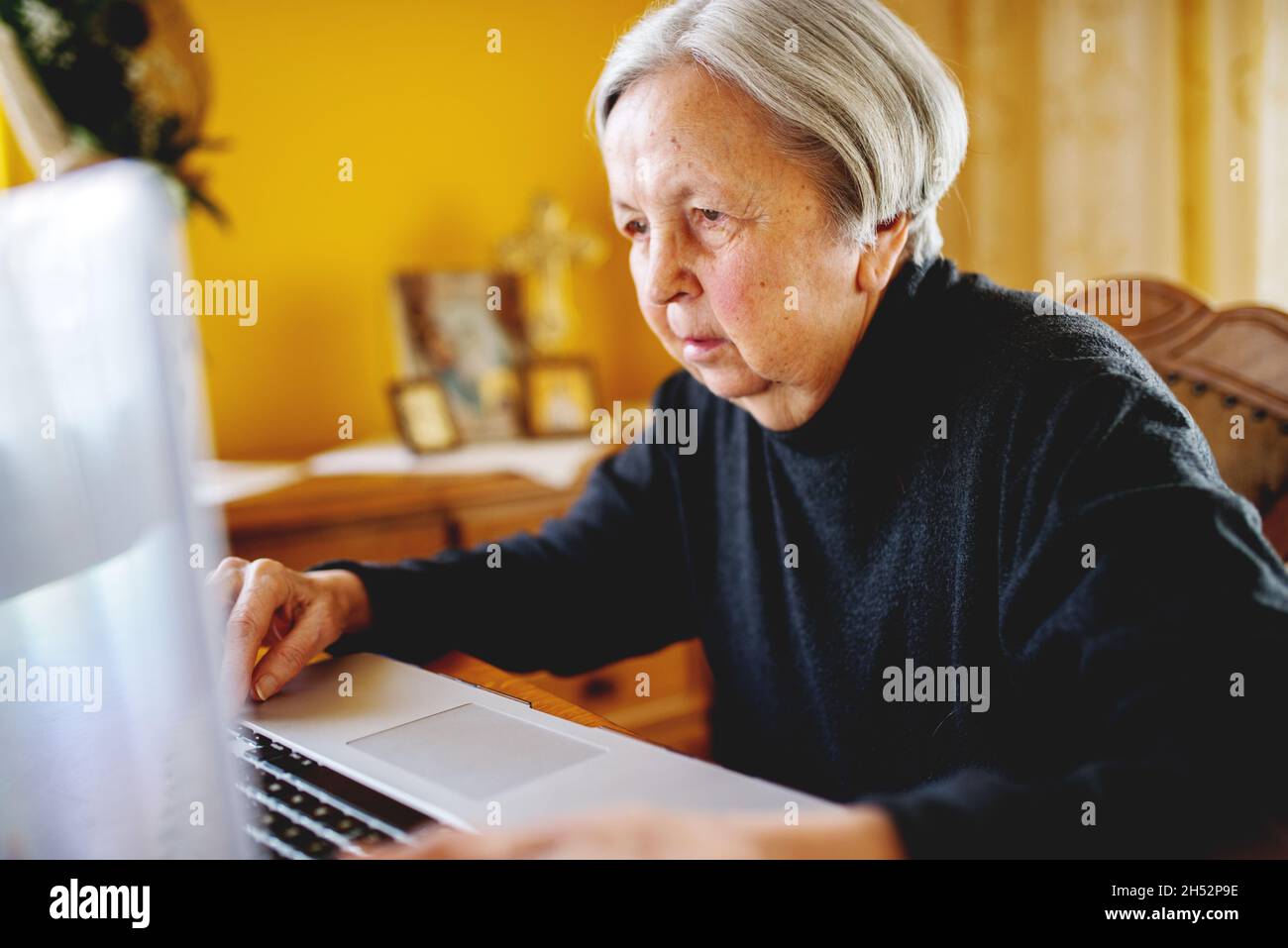 Grandmother surfing internet using laptop. She is looking at laptop ...