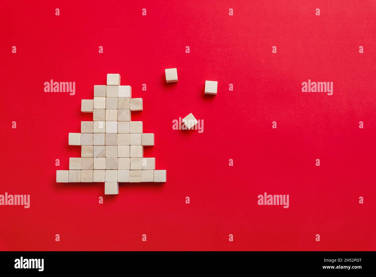 Christmas tree made of wooden cubes on a red table with free space for ...