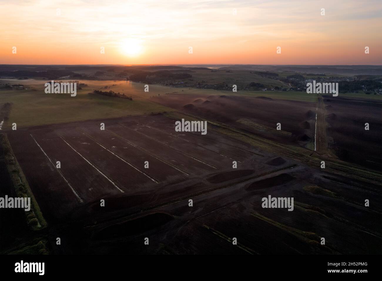Peat extraction site in fog on sunset. Collecting peat on peatlands ...