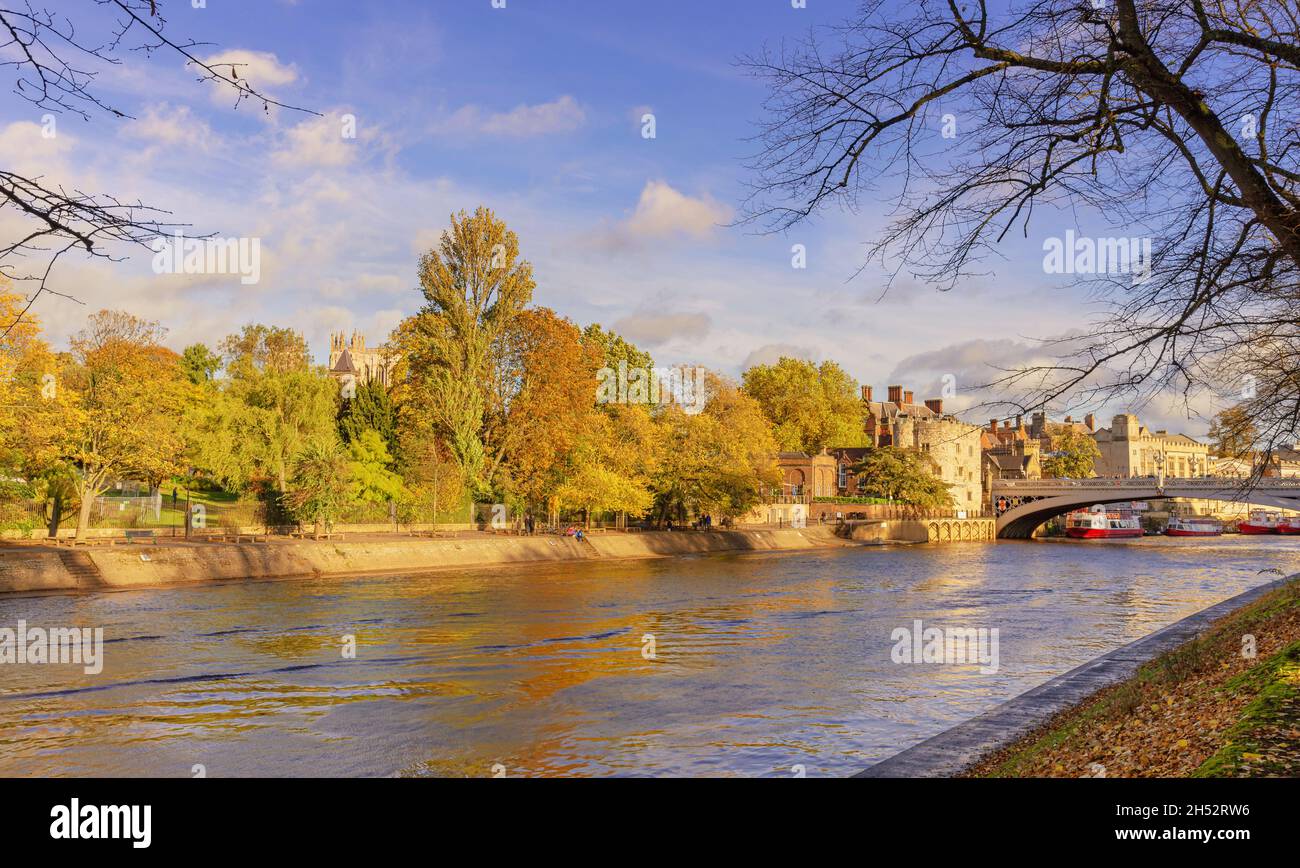 A riverbank scene in early autumn. A historic bridge is alongside an ...