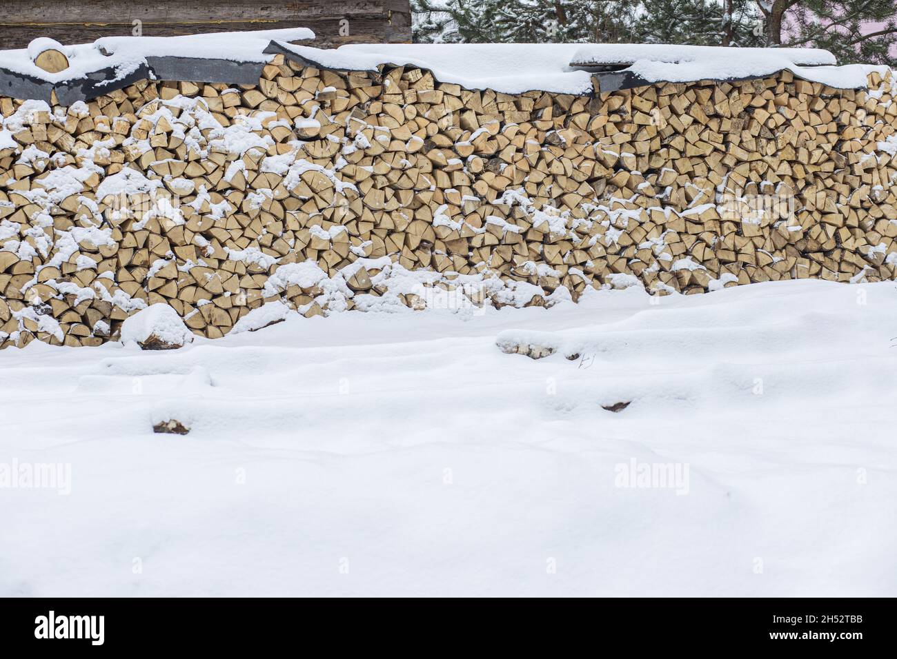 Firewood stacked in winter. Wood pile with snow stacked for firewood ...