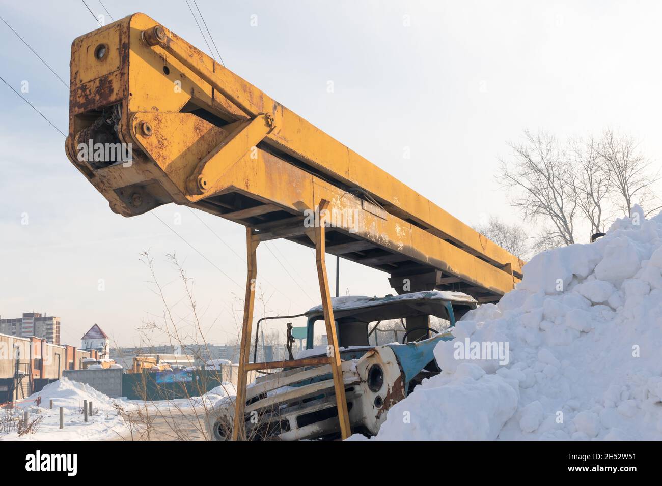 old broken rusty truck crane with yellow boom covered with snow on a ...
