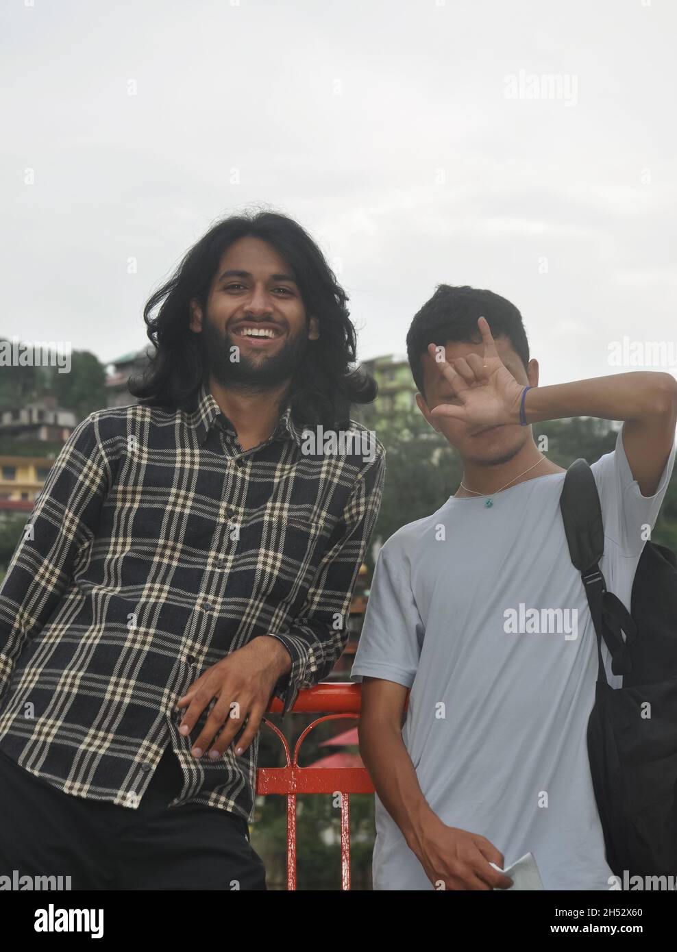 Two male friends standing together in outside with looking at camera. A ...