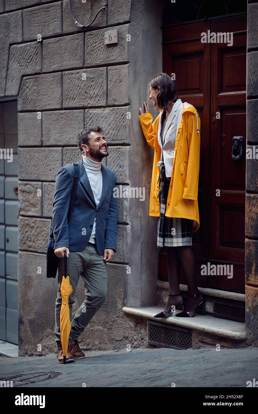 A young couple in love is standing on building entrance and chatting in ...