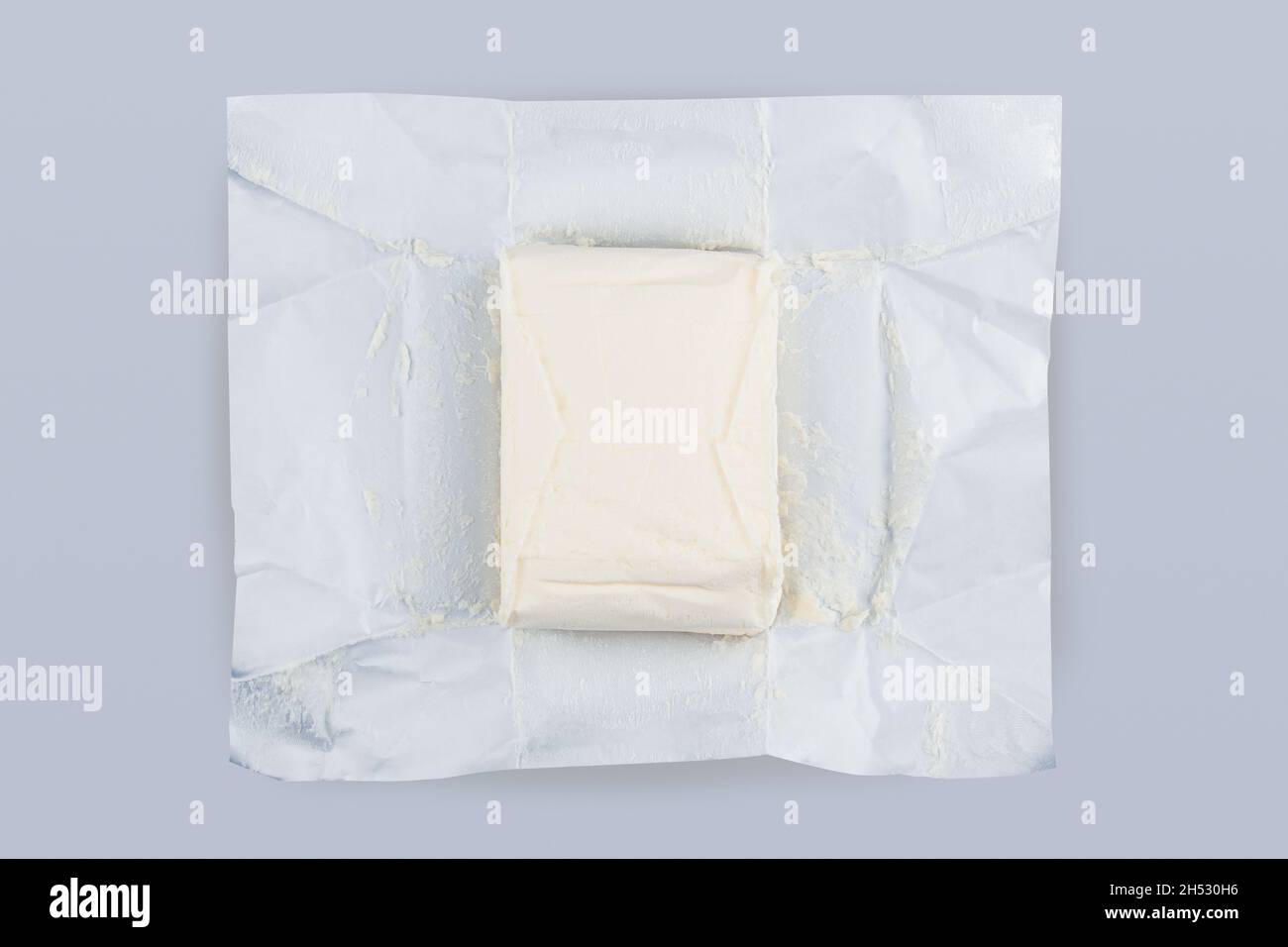 top view closeup of opened fresh piece of butter in silver foil ...